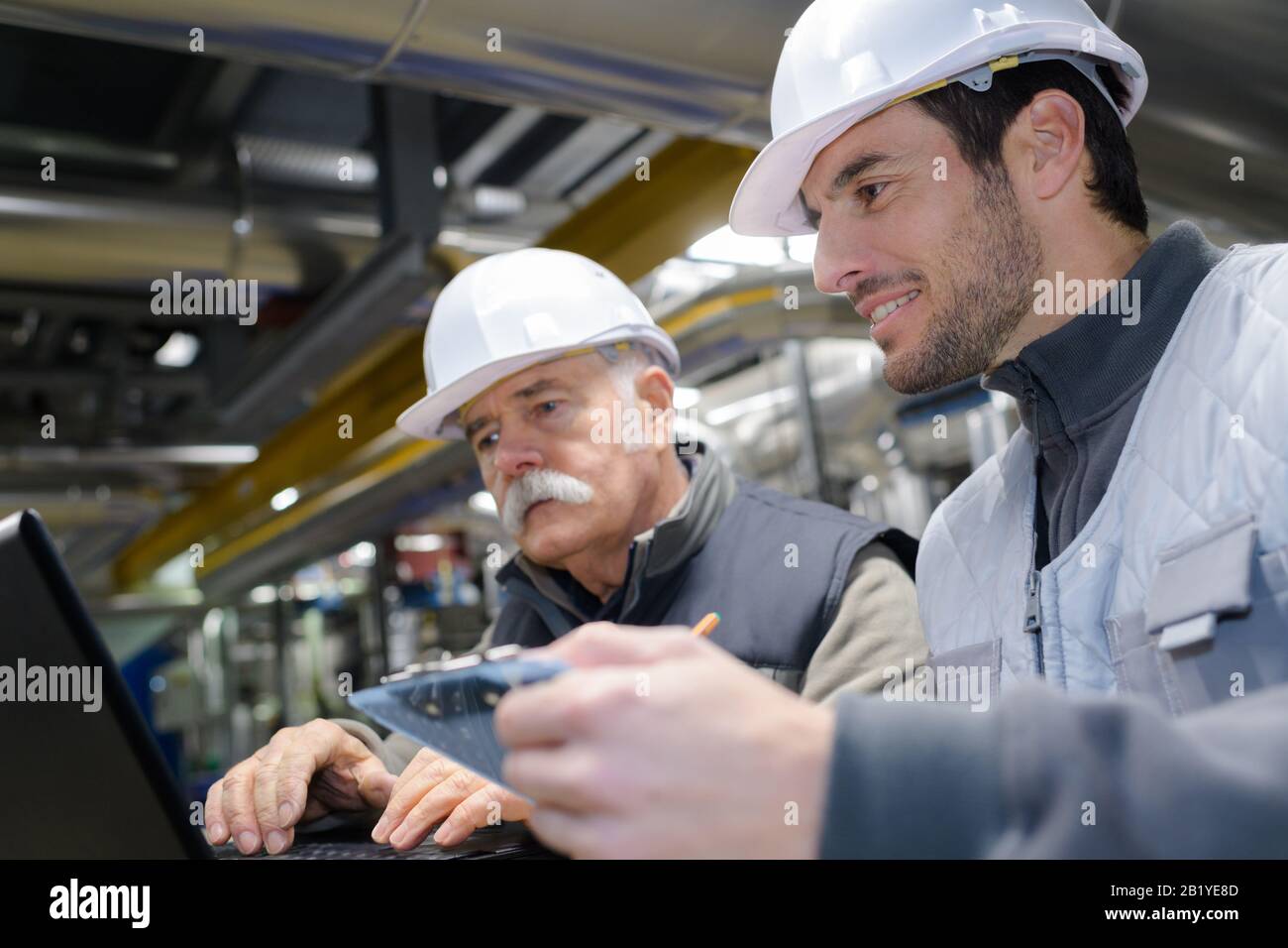 factory engineers looking at laptop Stock Photo - Alamy