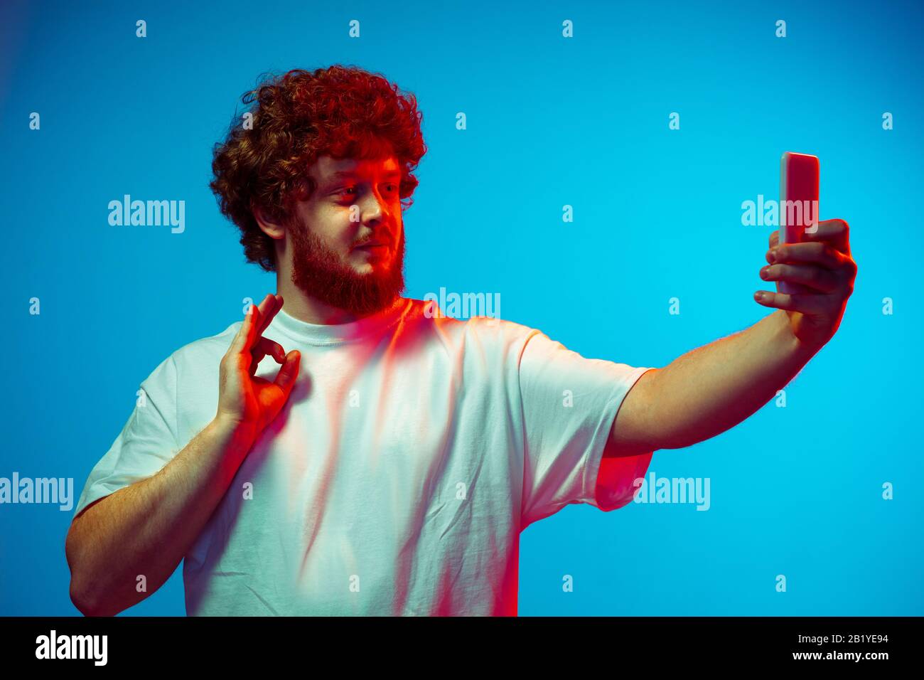 Taking selfie, vlog. Caucasian man's portrait isolated on blue studio ...