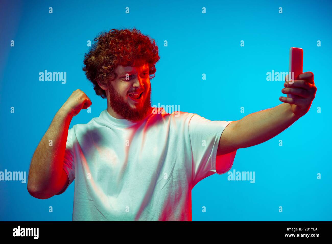 Taking selfie, vlog. Caucasian man's portrait isolated on blue studio ...