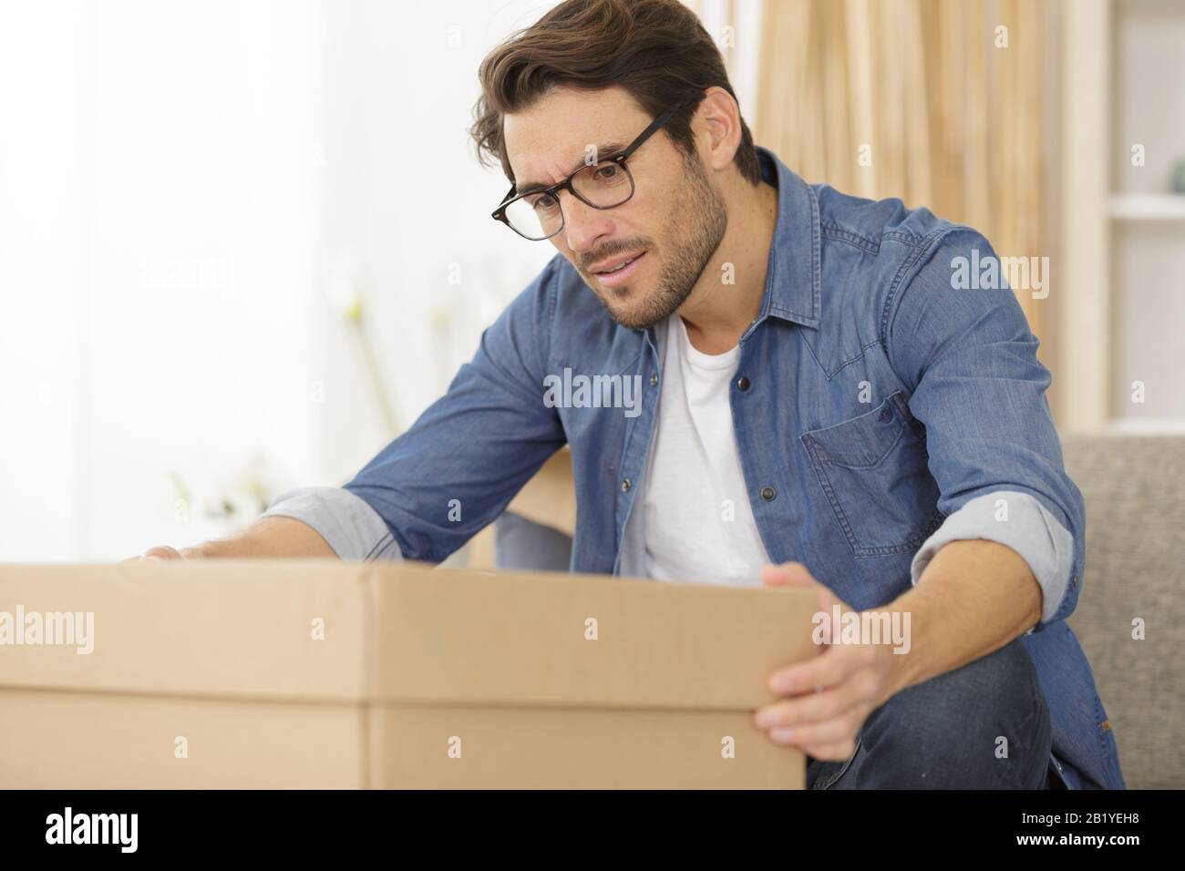 man at home opening a cardboard box Stock Photo - Alamy