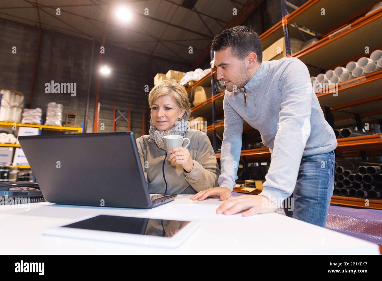 workers looking at laptop in warehouse Stock Photo - Alamy