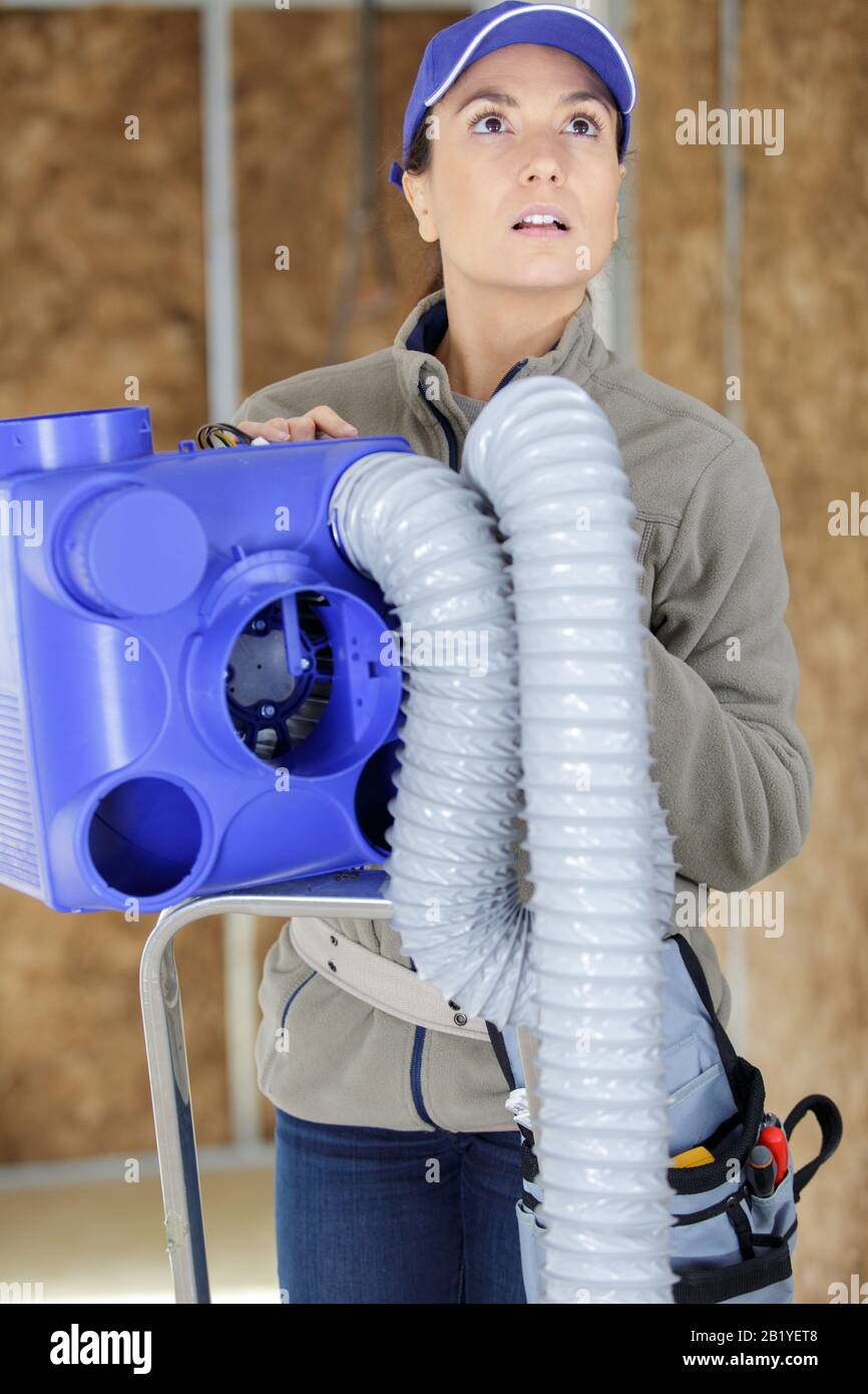 female worker holding a new air conditioning unit Stock Photo - Alamy