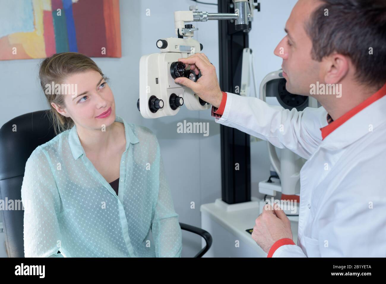 ophthalmologist talking to young woman in clinic Stock Photo - Alamy