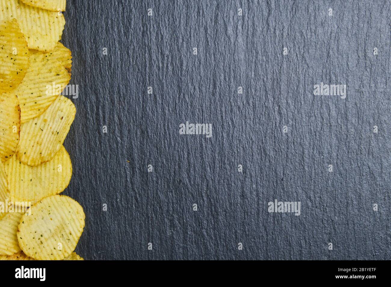 Potato chips are laid out on slate dishes in the left corner. Top view ...