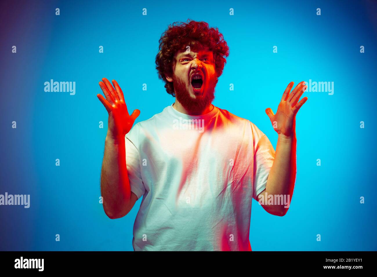 Calling, shouting. Caucasian man's portrait isolated on blue studio ...
