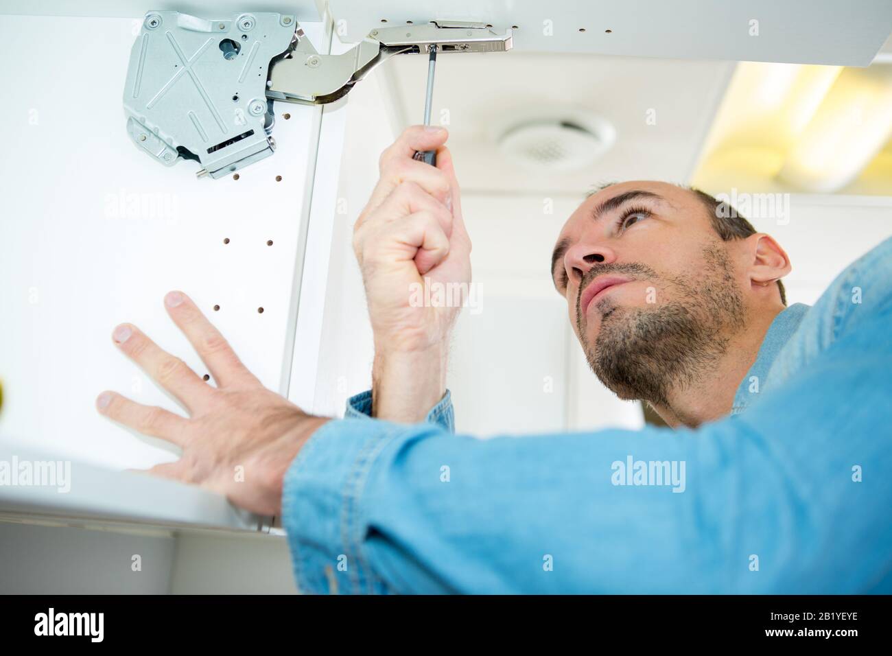 kitchen installer doing carpenter work Stock Photo - Alamy