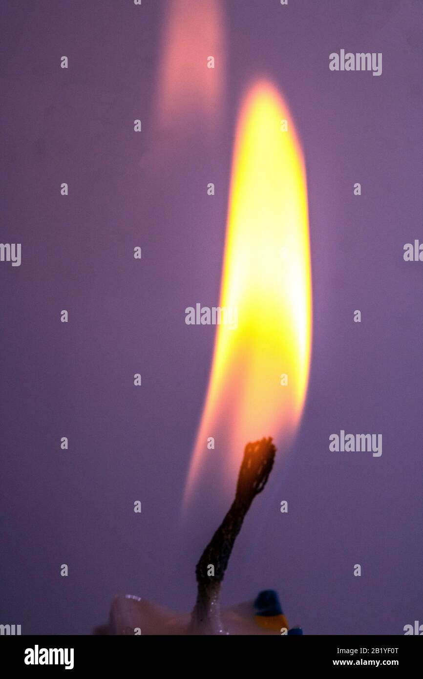 A Close Up of a Single Candle Flame and Wick on Coloured Background ...