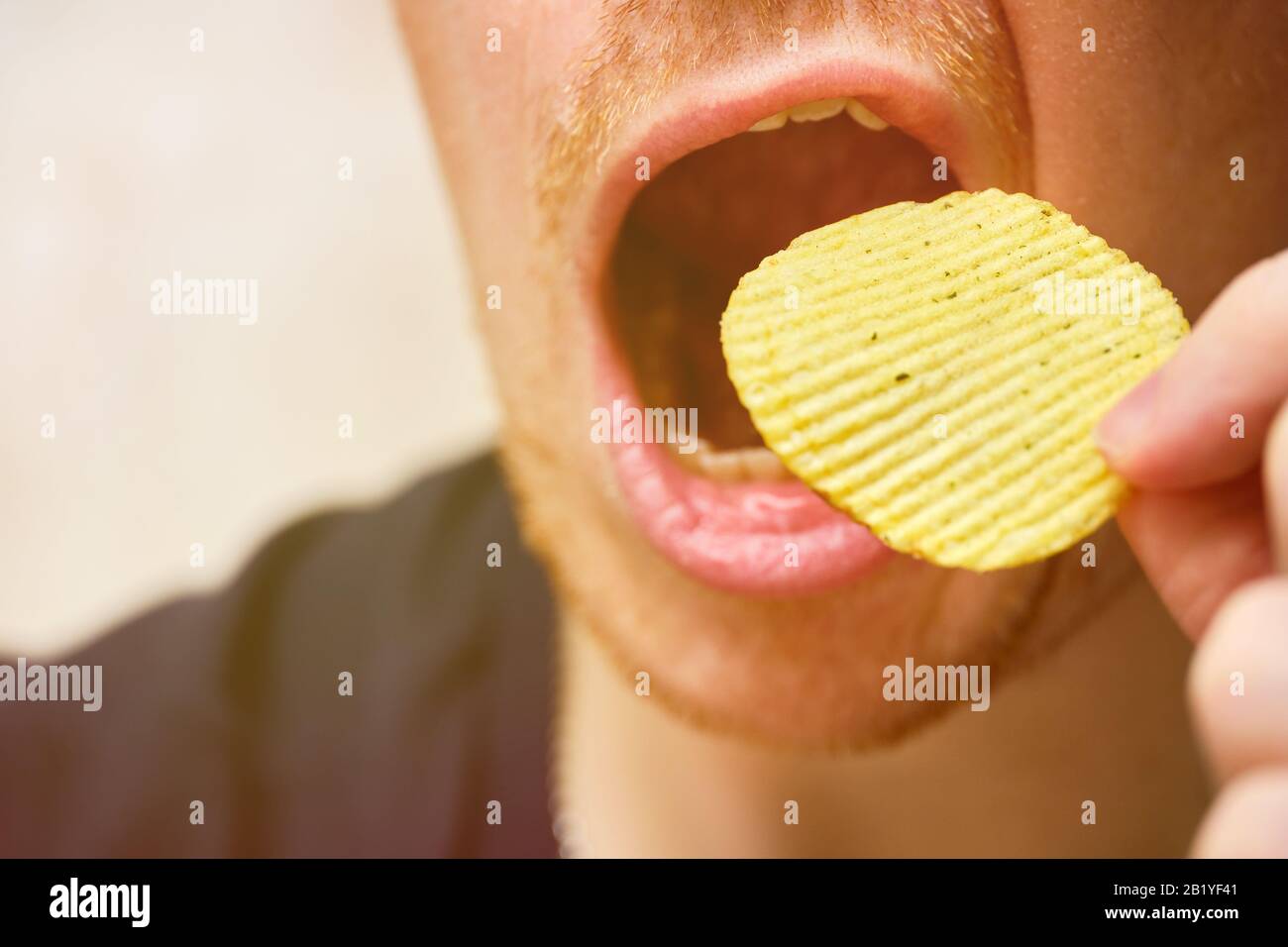 The man opens his mouth, bringing chips to it. Close up Stock Photo - Alamy