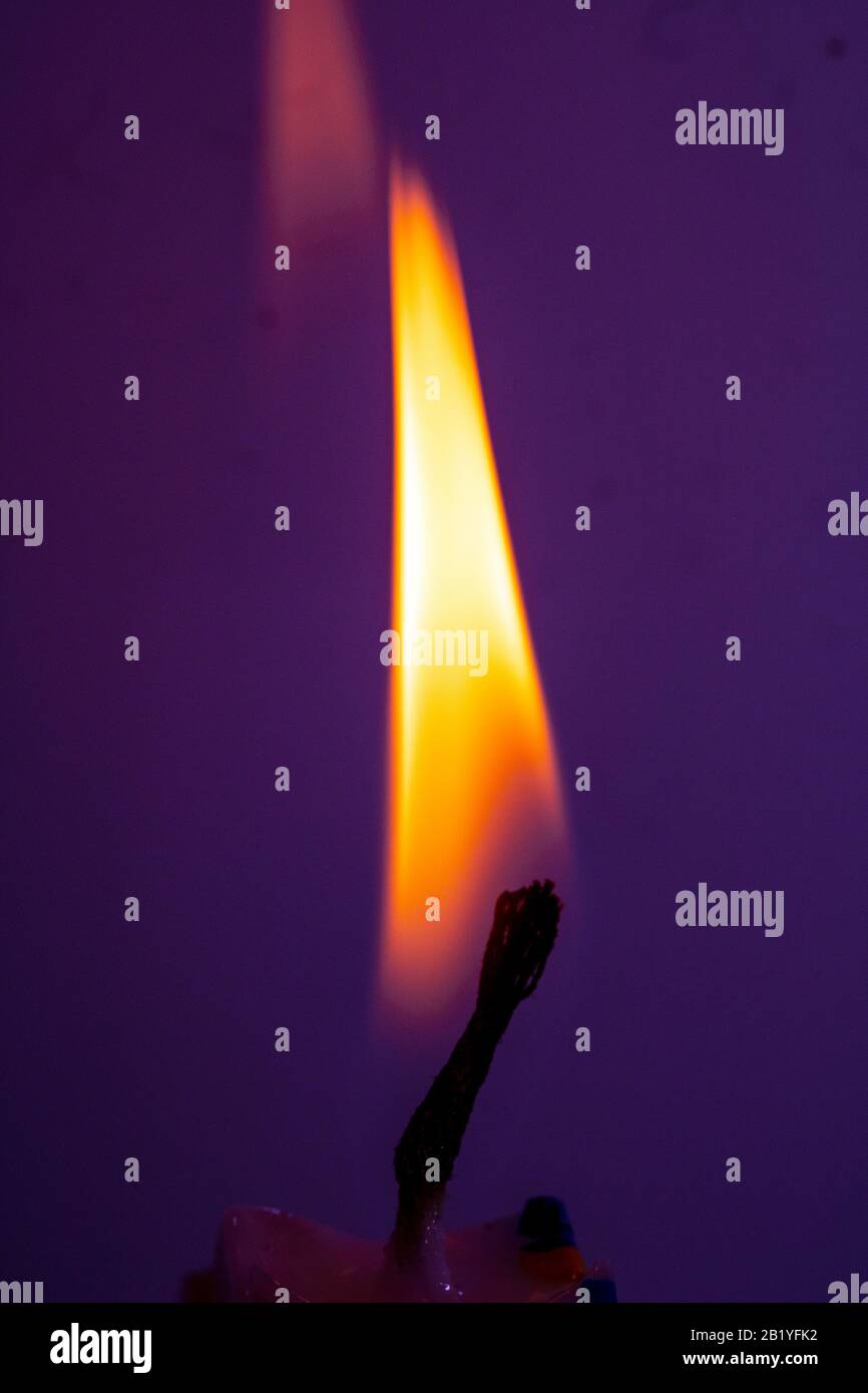 A Close Up of a Single Candle Flame and Wick on Coloured Background ...