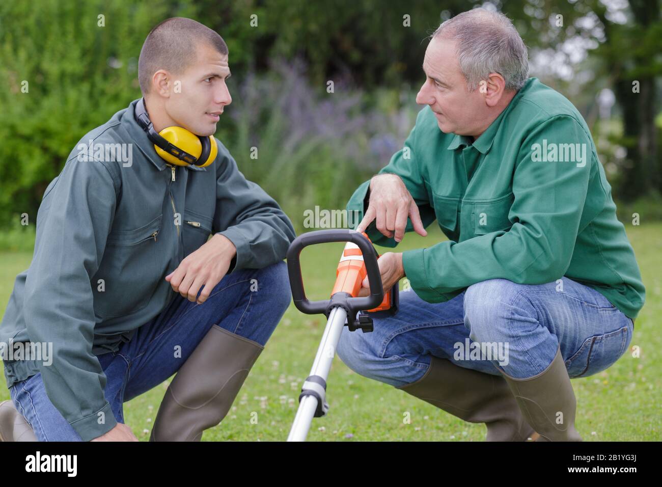young gardener being shown how to operate a strimmer Stock Photo - Alamy