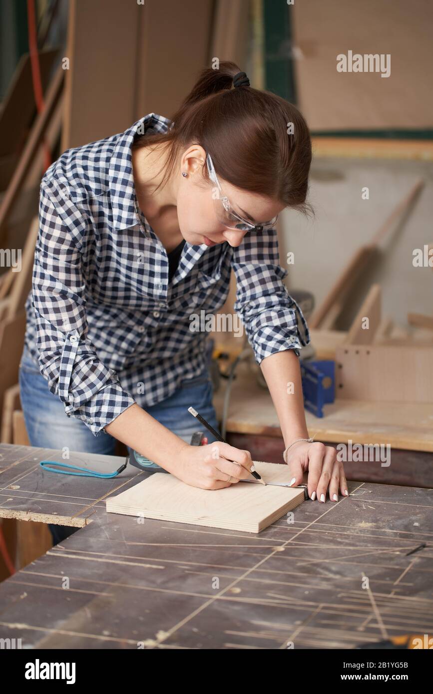 Close up carpenter girl in glasses with tape measure and blackboard in ...