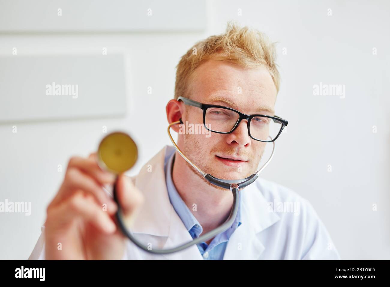 Doctor with stethoscope listening in his practice Stock Photo - Alamy