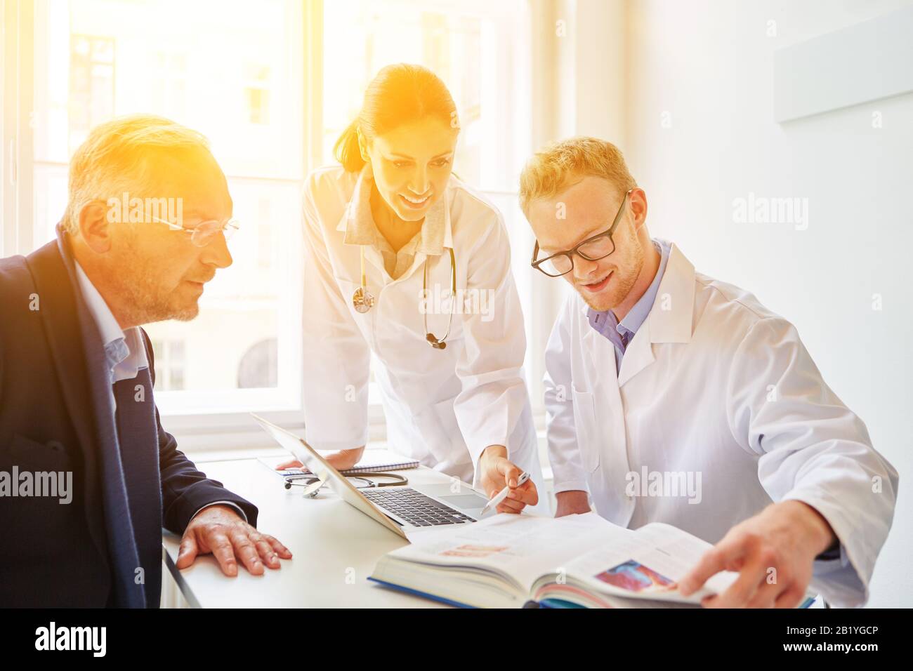 The doctor looks into a medical dictionary during the consultation ...