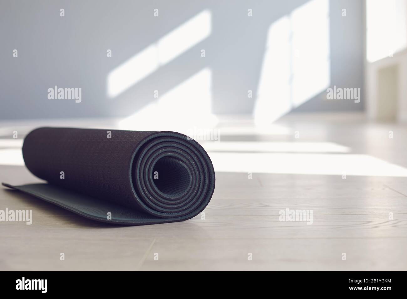 Black yoga mat on the floor of a bright sunny studio Stock Photo - Alamy