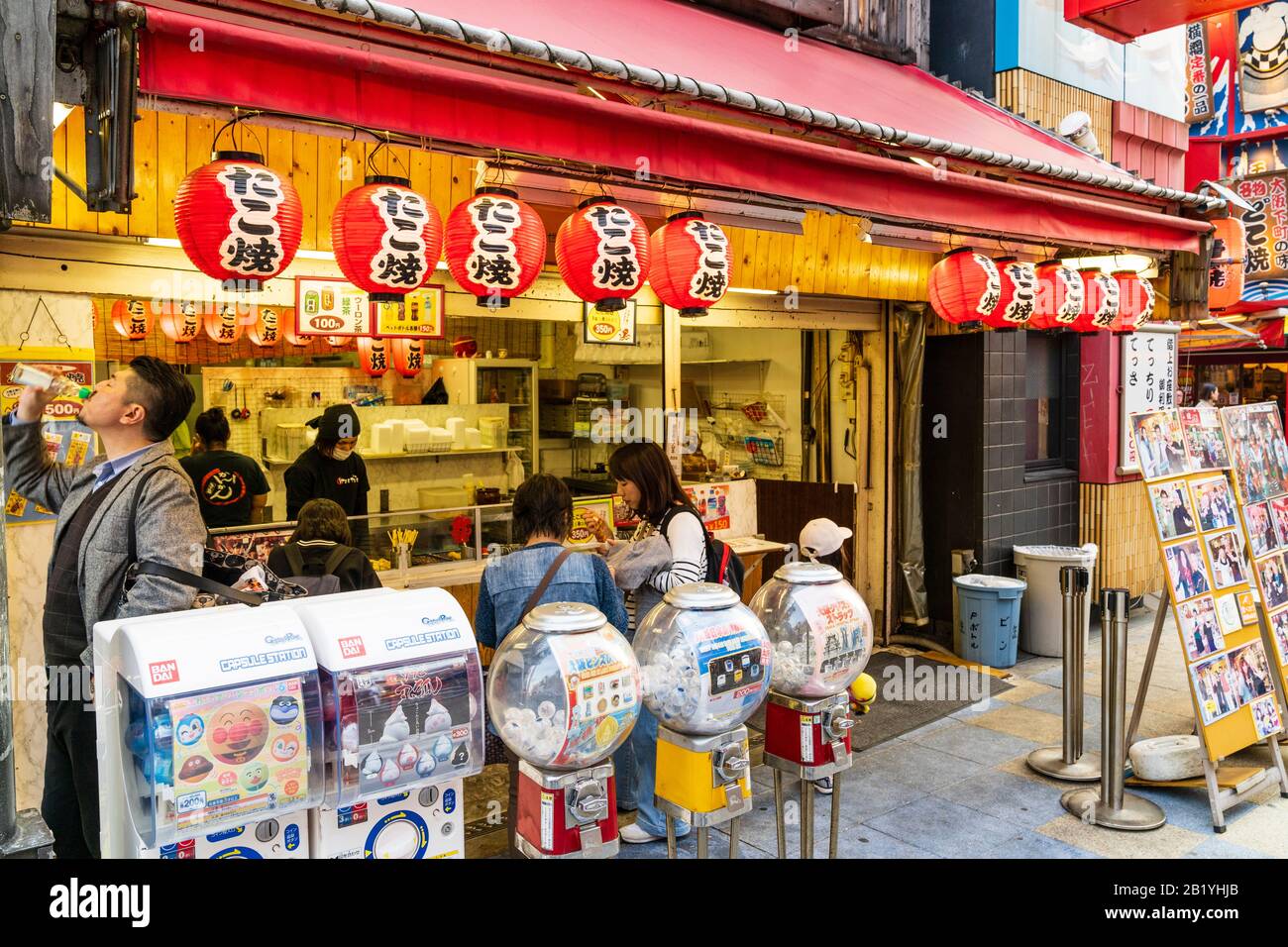 Shinsakei district, Osaka. People at take away takoyaki counter with ...