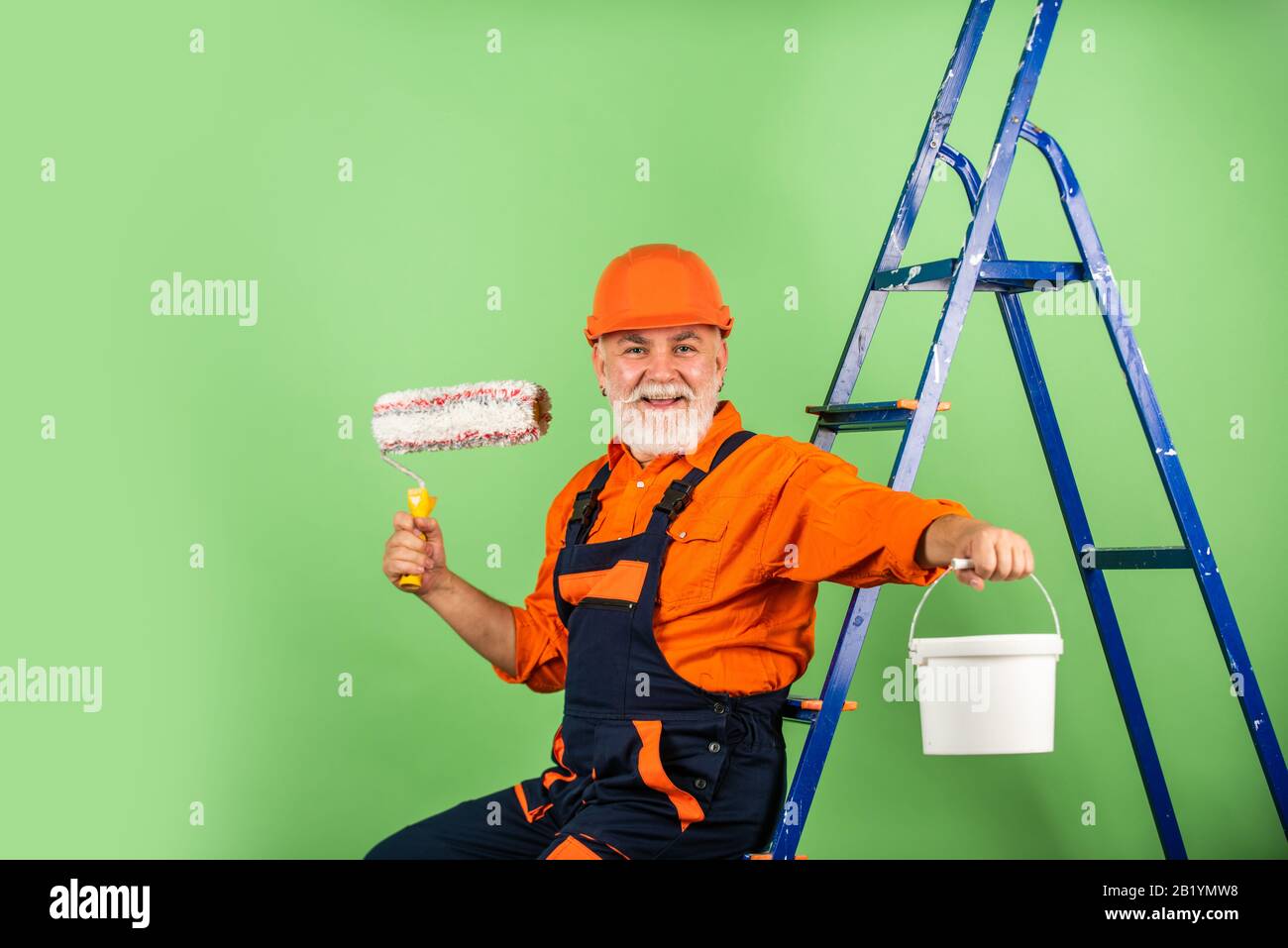 To make repairs. man in working clothes painting wall in empty room ...