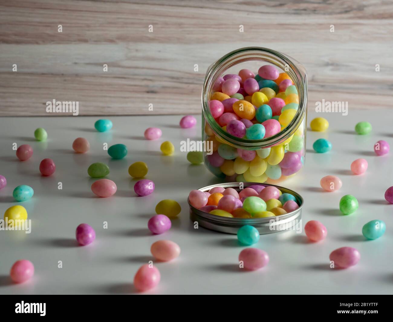 Easter jelly beans spilling from candy jar onto a white countertop ...