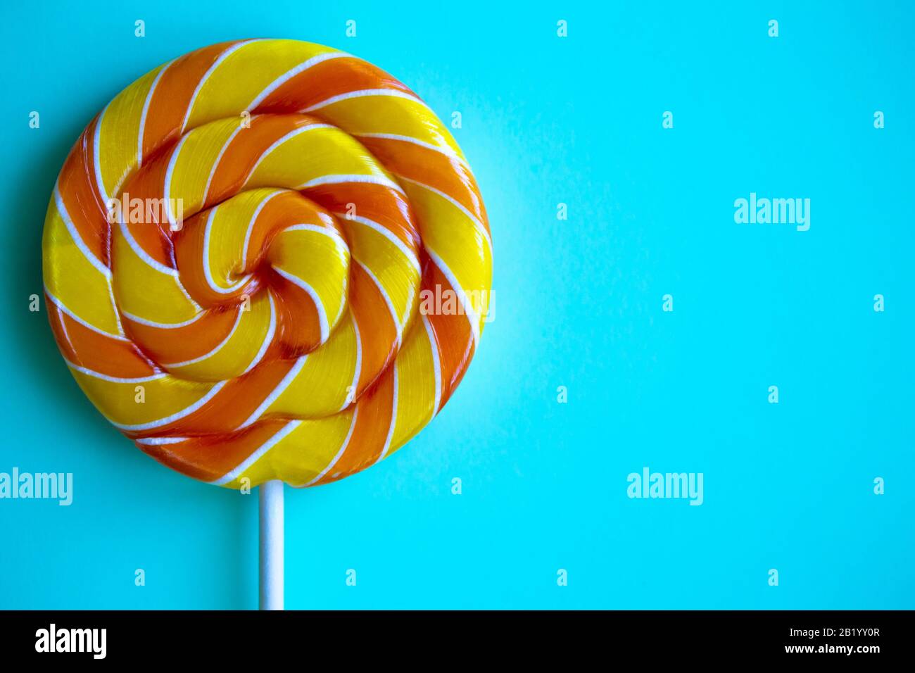 Bright swirl lollipop on blue background with copy space. Festive ...