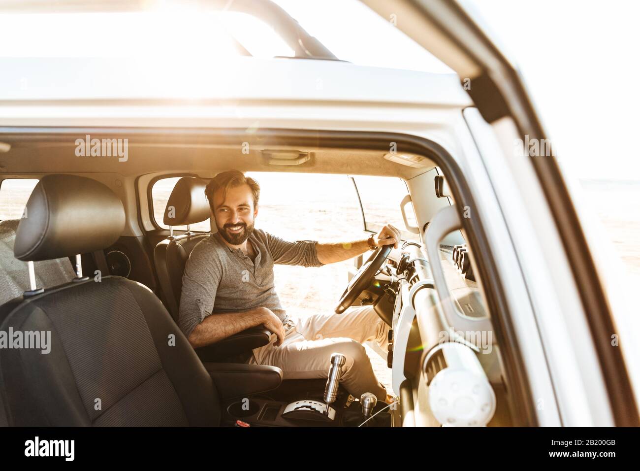 Image of handsome positive young man drive the car outdoors at the ...