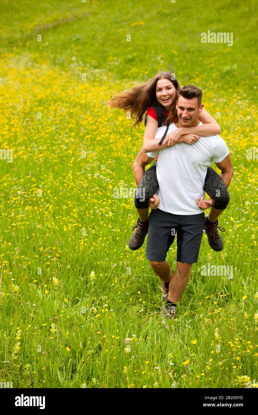 active Playful coupel hiking on a meadow in ratly spring green grass ...