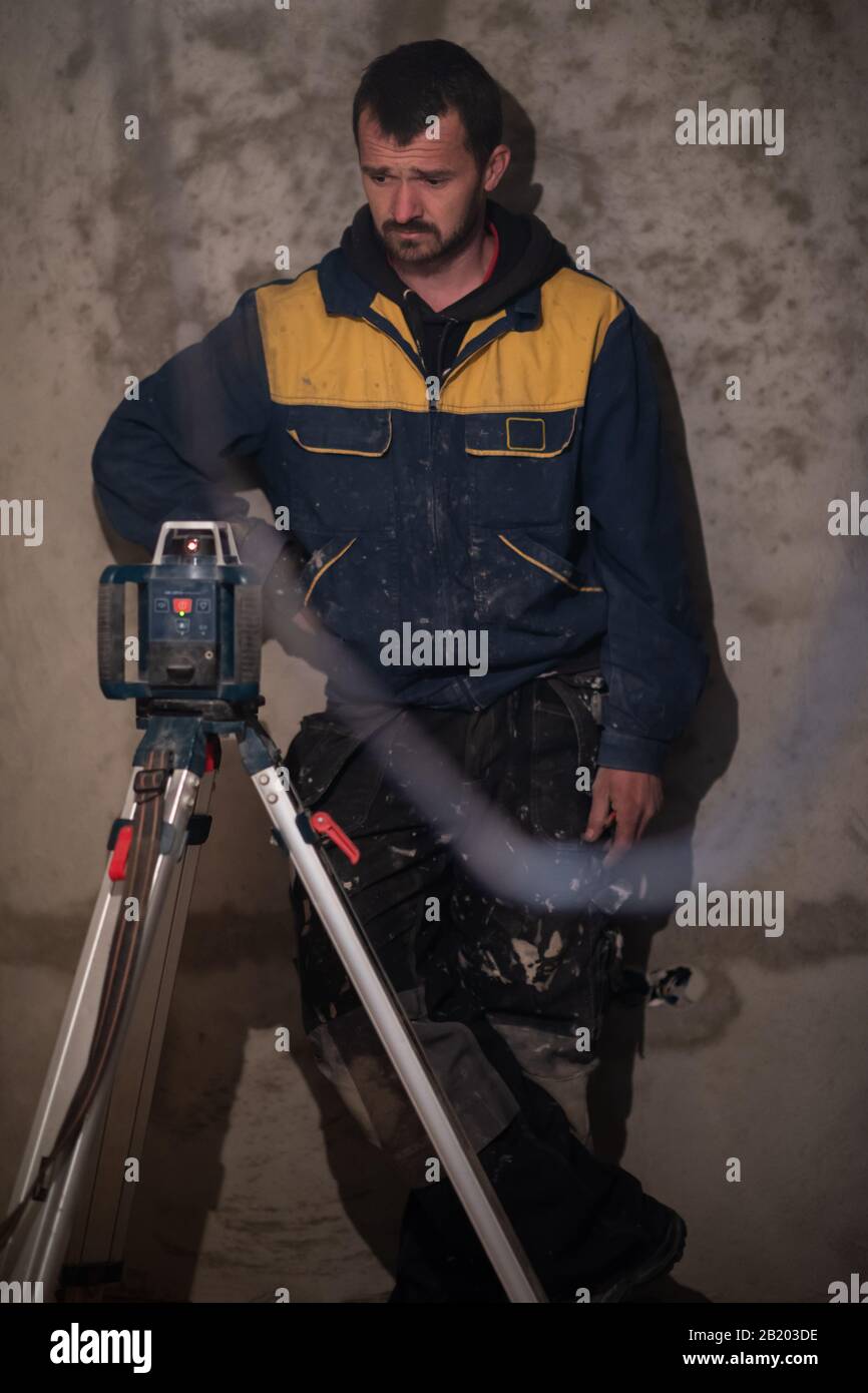 professional worker using laser level in a building under construction ...
