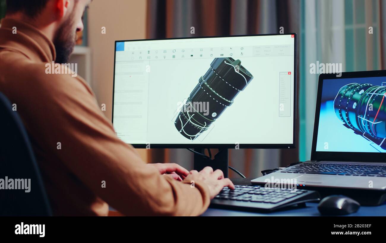 Young engineer looking closely at turbine project while working from ...
