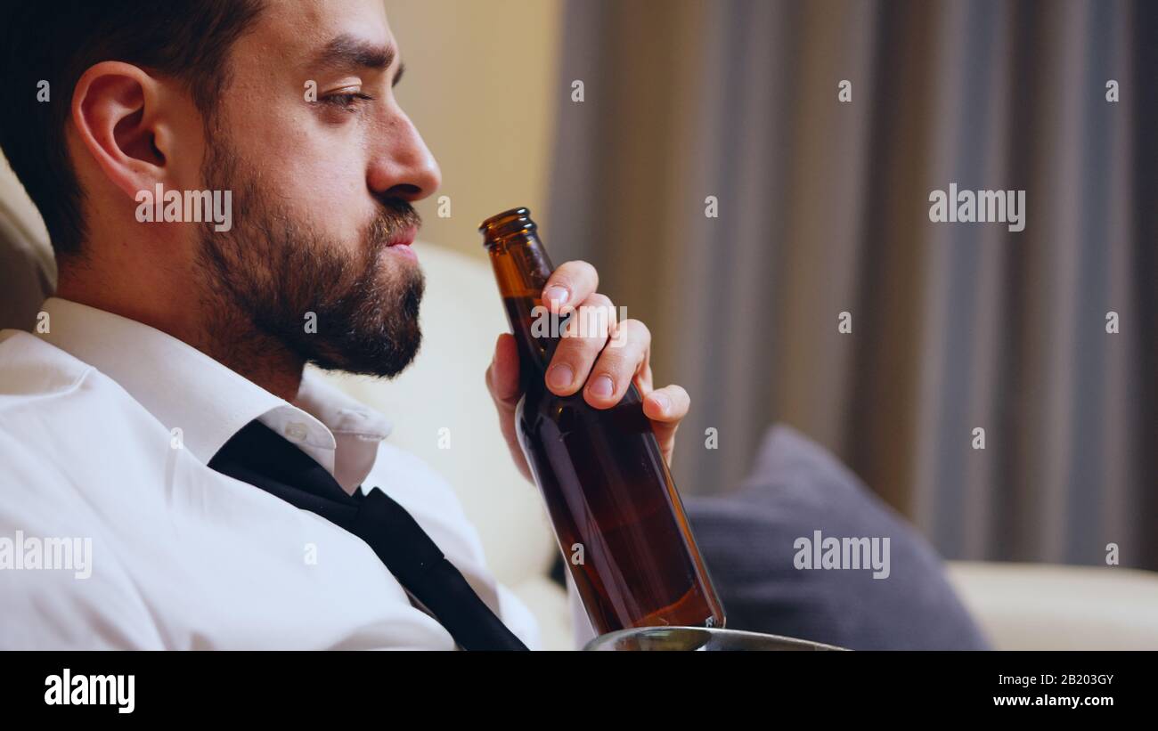 Side view of businessman drinking beer after work in his apartment ...