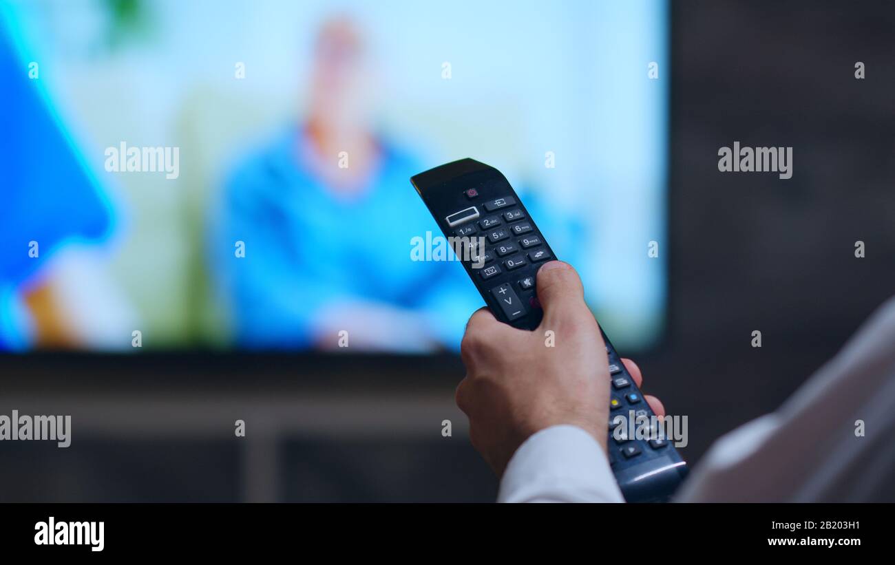 Back view of businessman using tv remote control sitting on couch in ...