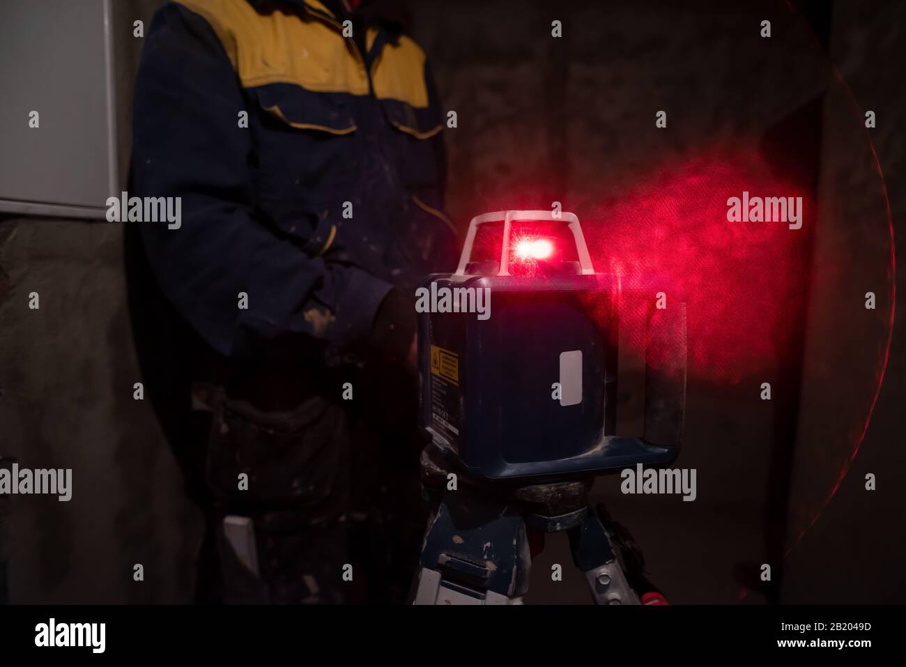 professional worker using laser level in a building under construction ...
