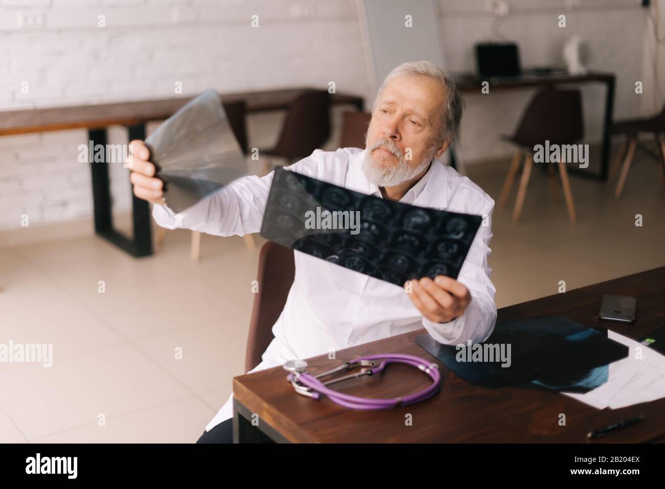 Adult male doctor examining x-ray and MRI scan at a table Stock Photo ...