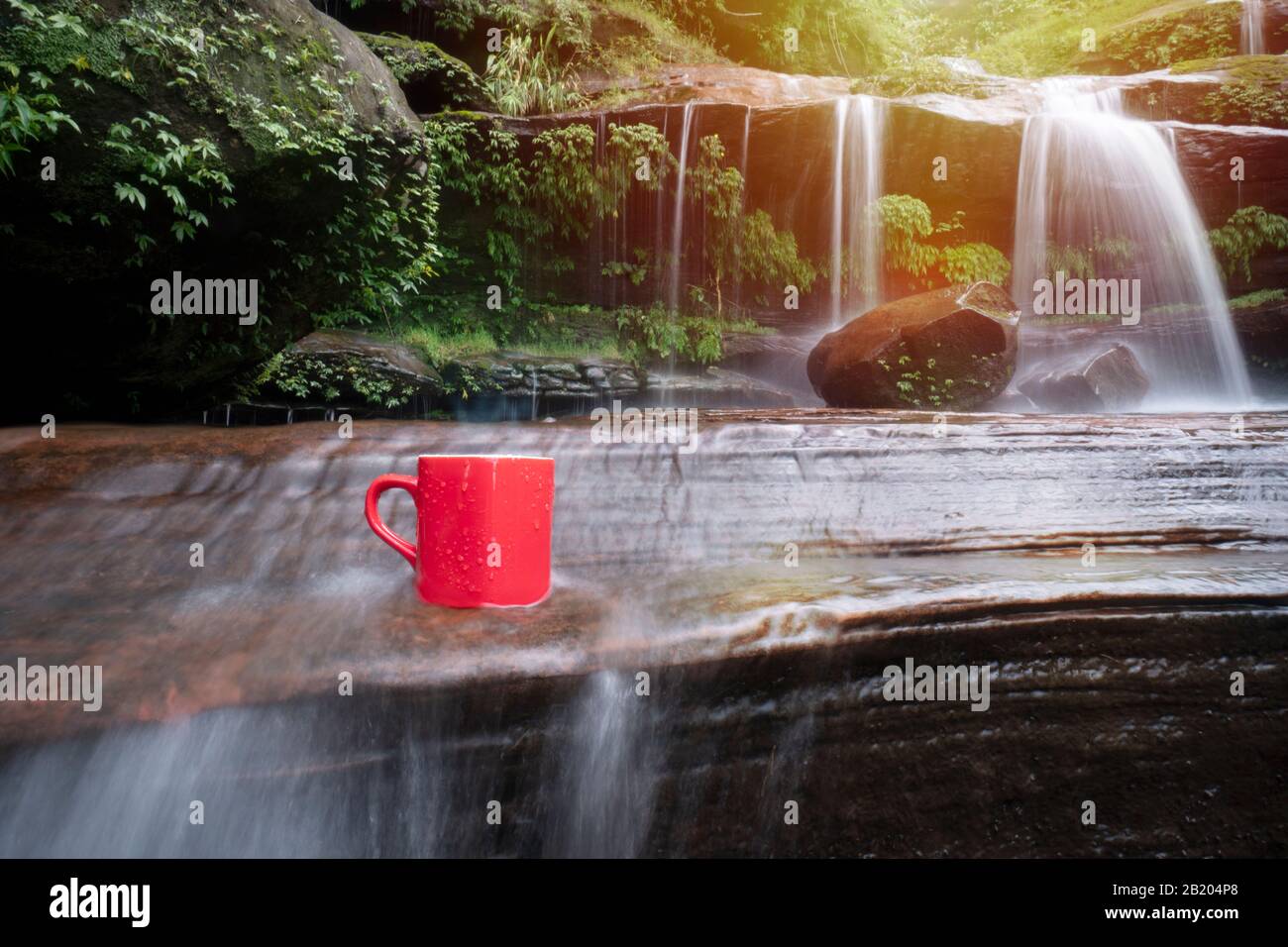 red cup of coffee with waterfall nature background Stock Photo - Alamy