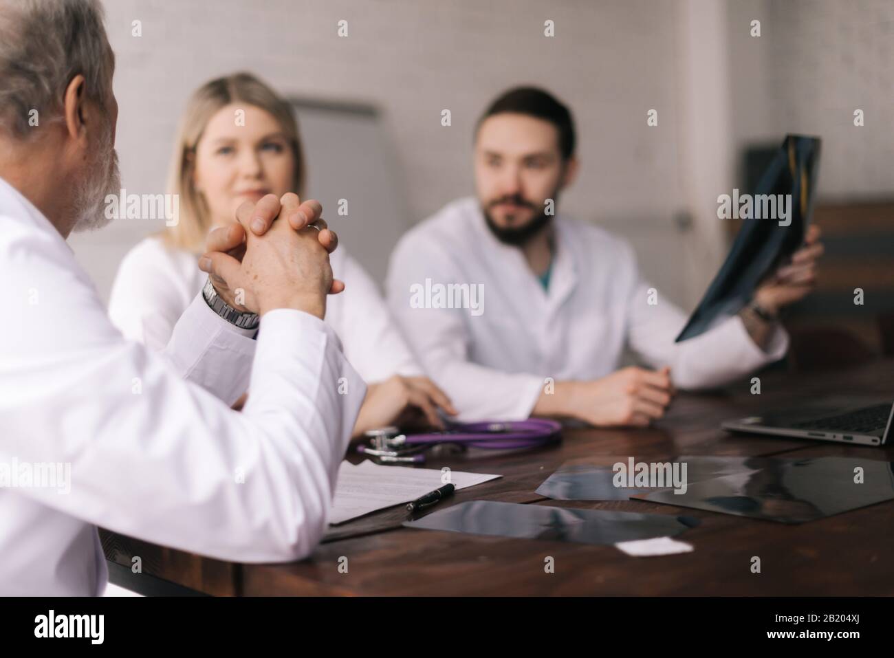 Team of three adult and young medical specialists discuss chest X-rays ...