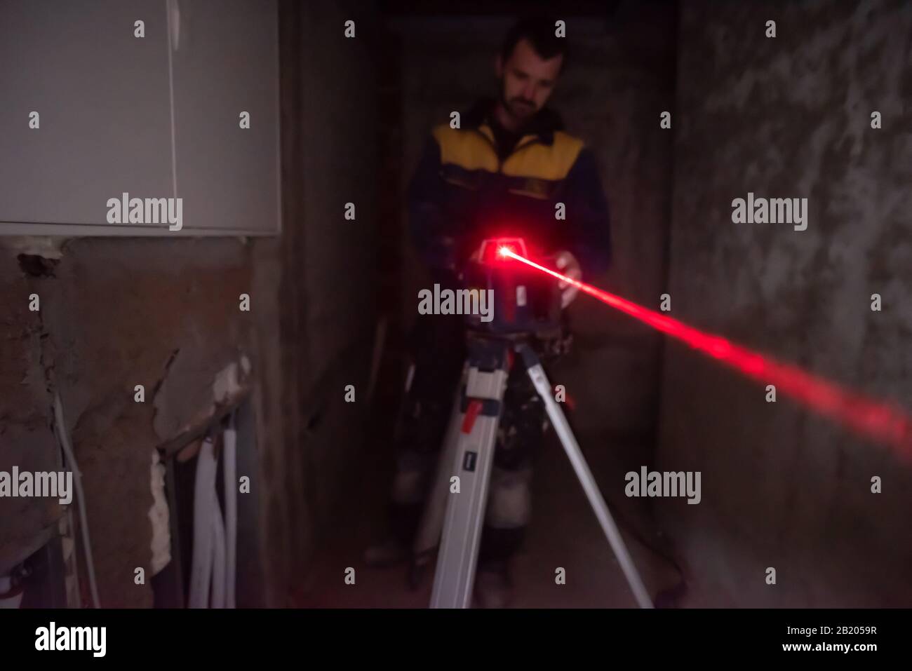 professional worker using laser level in a building under construction ...