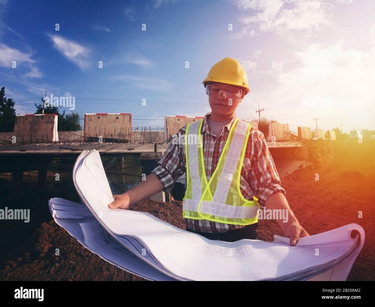 Engineer holding blueprint in construction site Stock Photo - Alamy