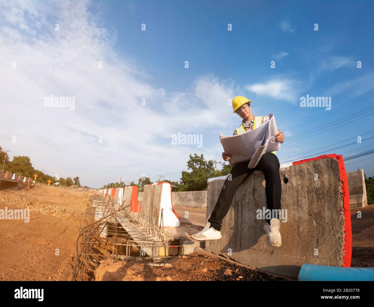 Engineer holding blueprint in construction site Stock Photo - Alamy