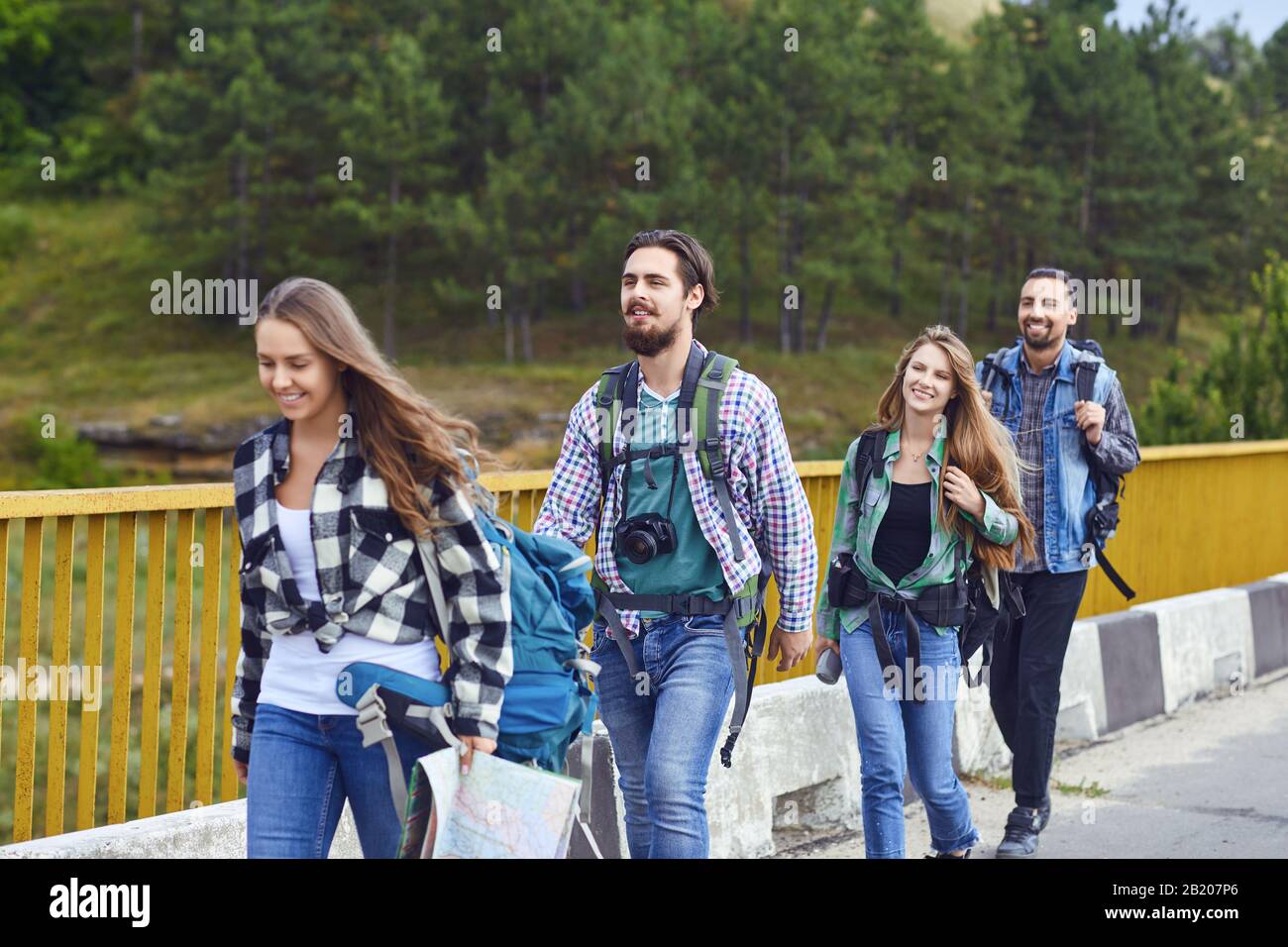 Young people with backpacks stand in the forest from behind Stock Photo ...