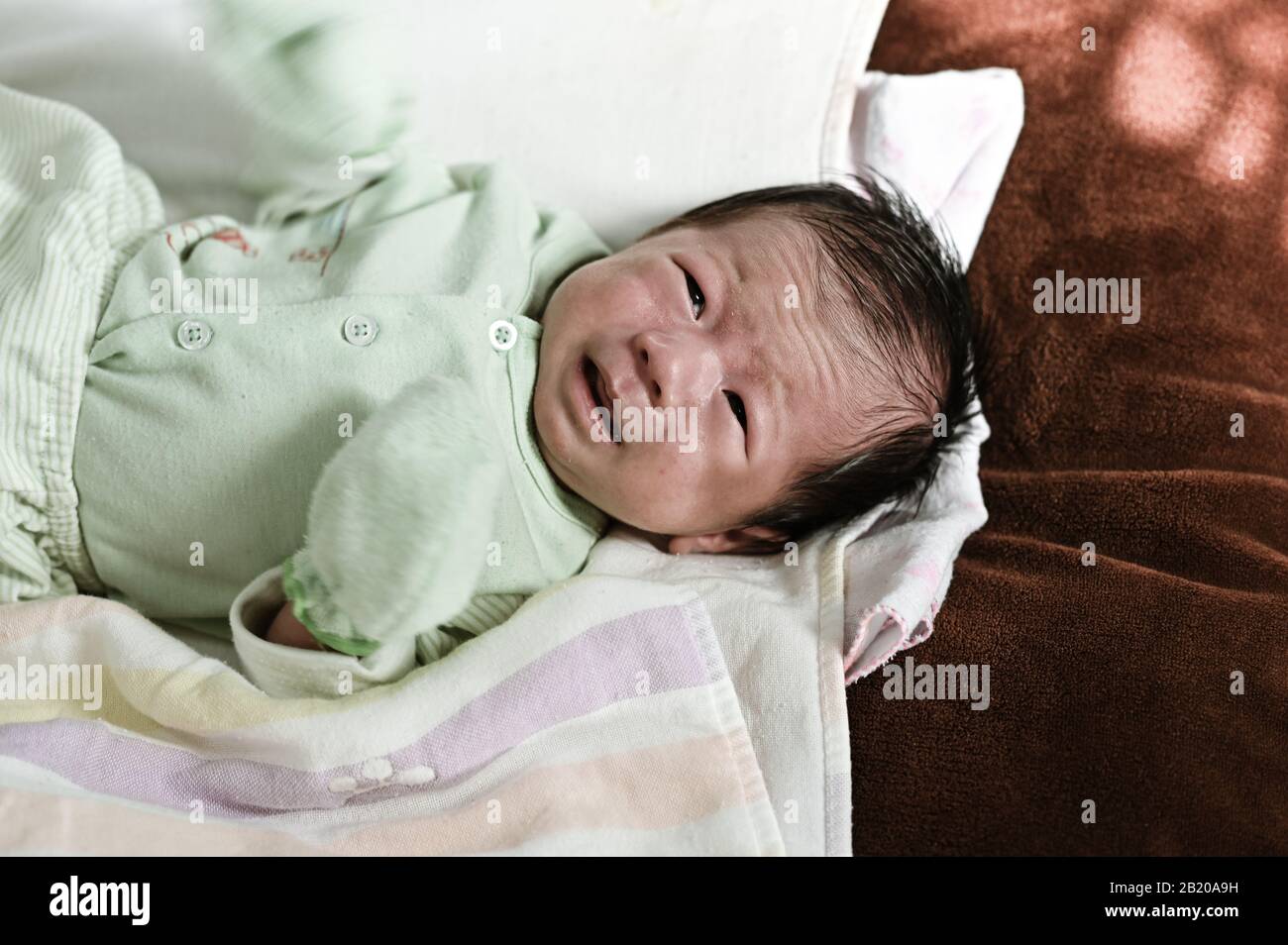 Adorable newborn baby crying while lying at the comfortable nappy bed ...