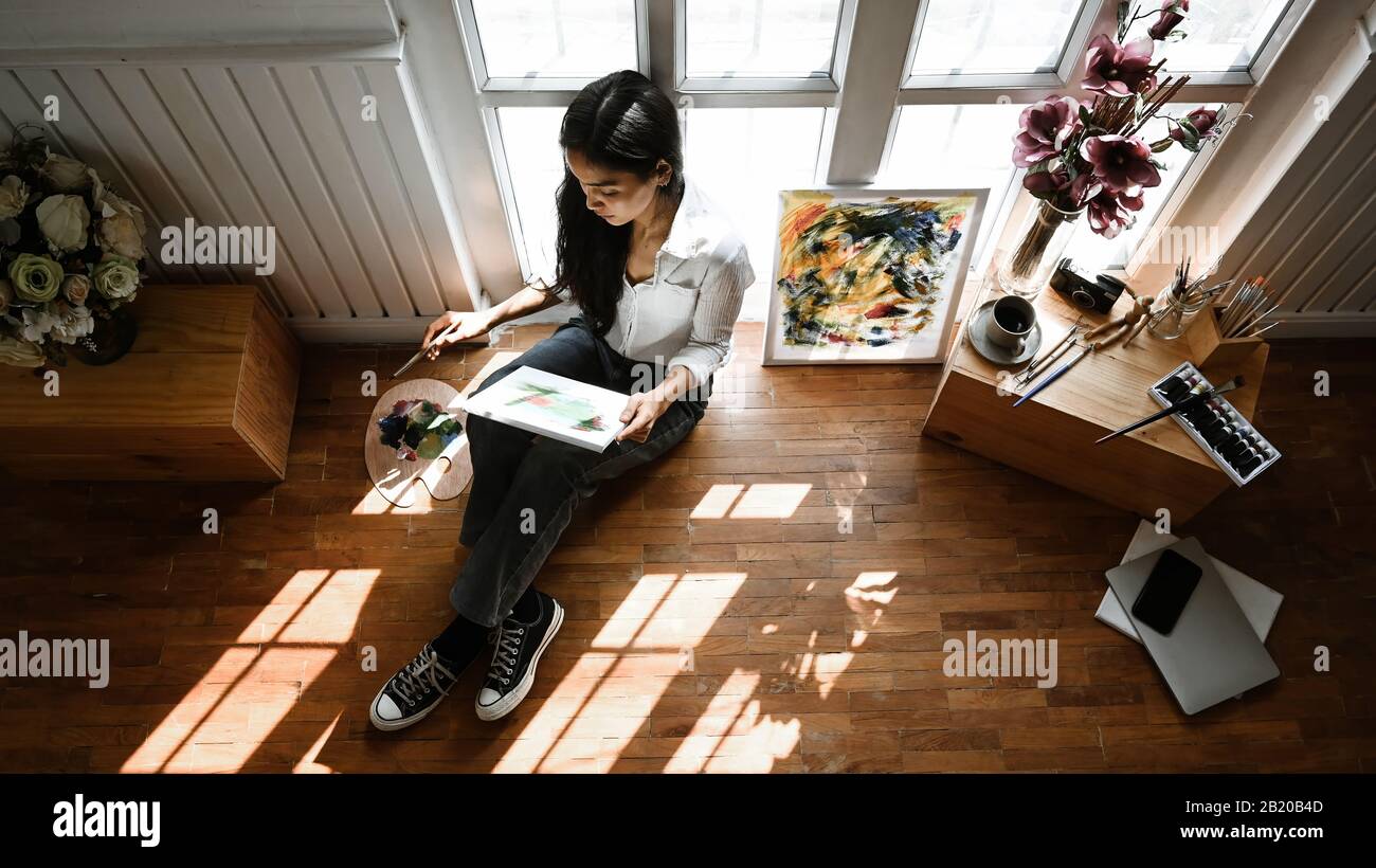 Young artist girl sitting and lean on windows while looking ...