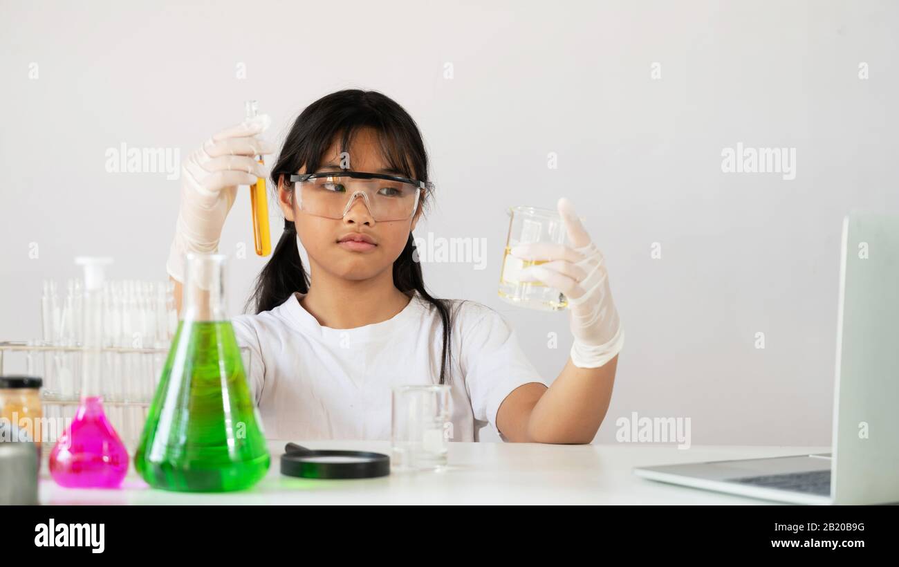 Photo of young adorable girl in safety glasses and gloves holding a ...