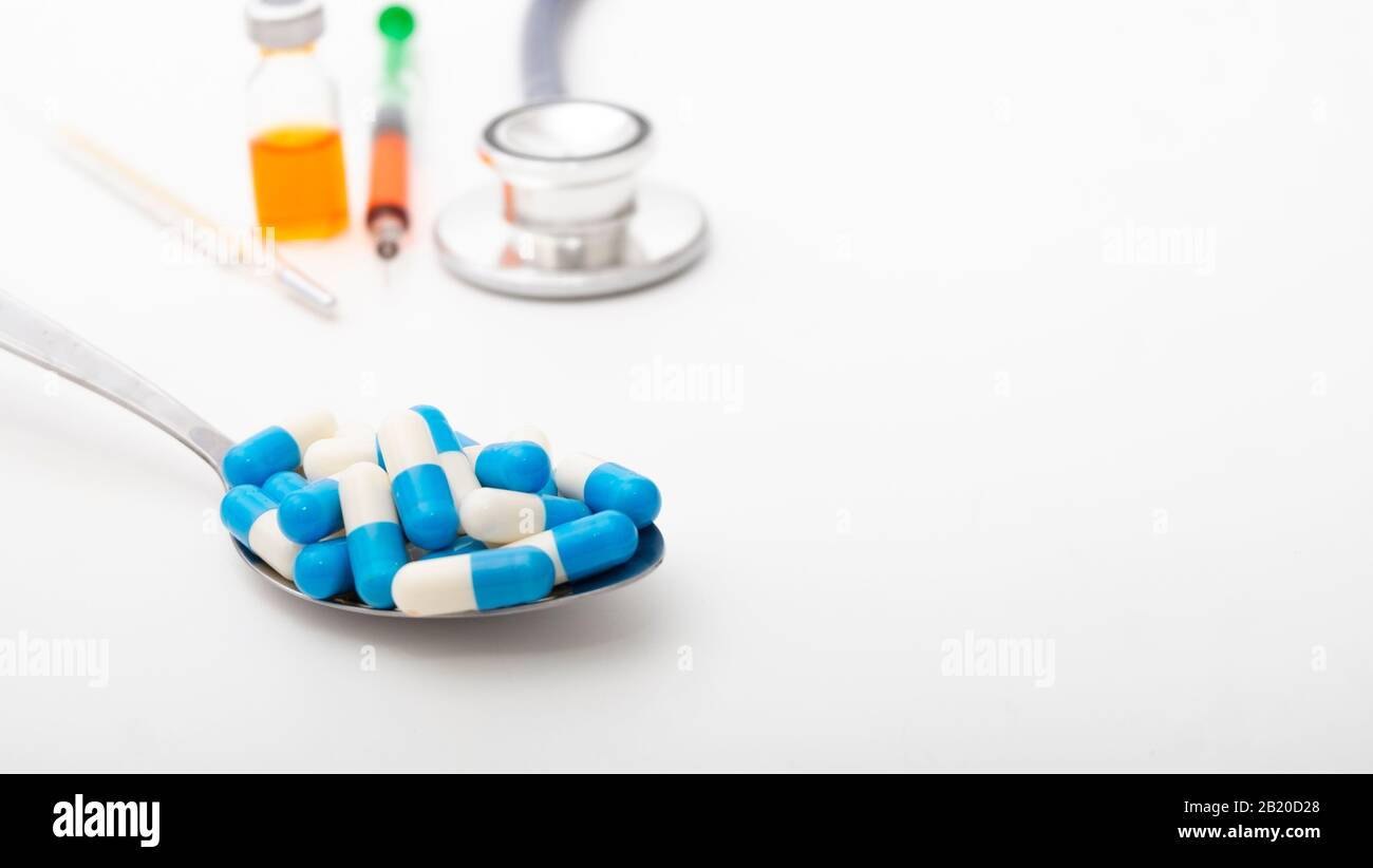 Medical drug capsule on spoon with medical tool on white background ...