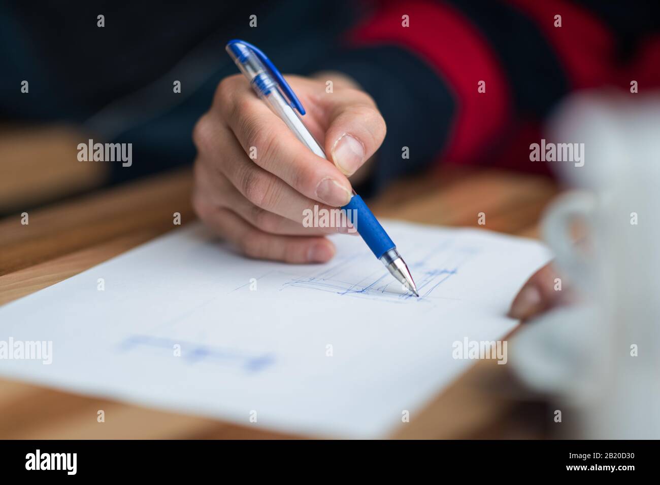 The hand of the designer with a pen, designing and sketching his idea ...