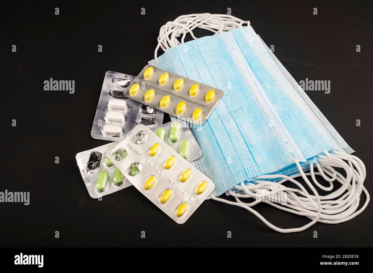 Medical disposable masks and several packages of pills on a black ...