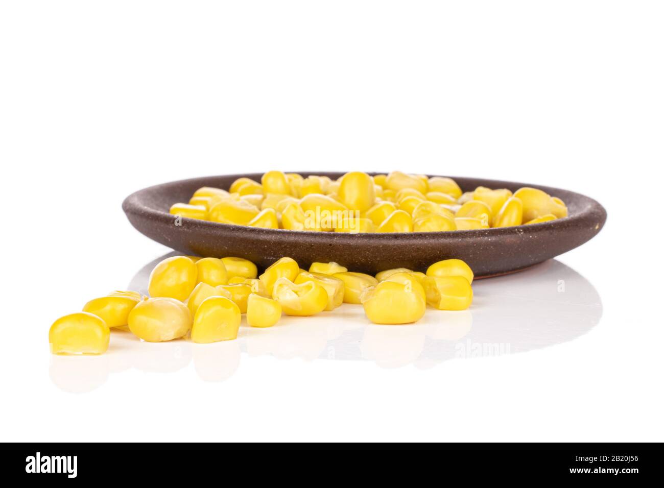 Lot of pieces of bright canned yellow corn with brown ceramic coaster ...