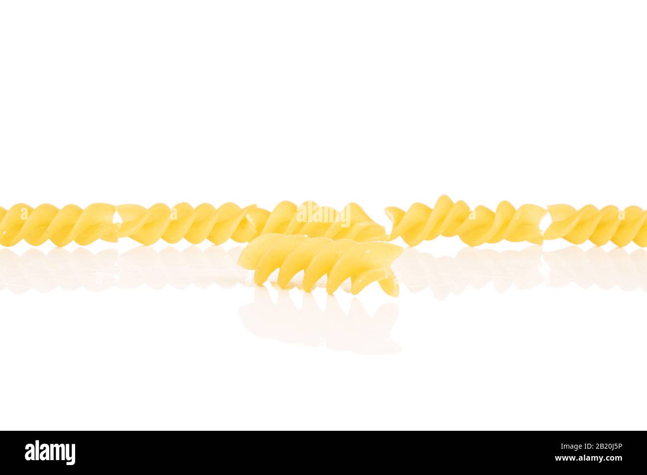 Lot of whole yellow pasta fusilli one in front isolated on white ...