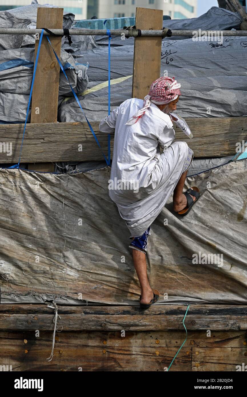 dubai, uae - 2020.02.22: the captain of an arab wooden dhow climbing ...