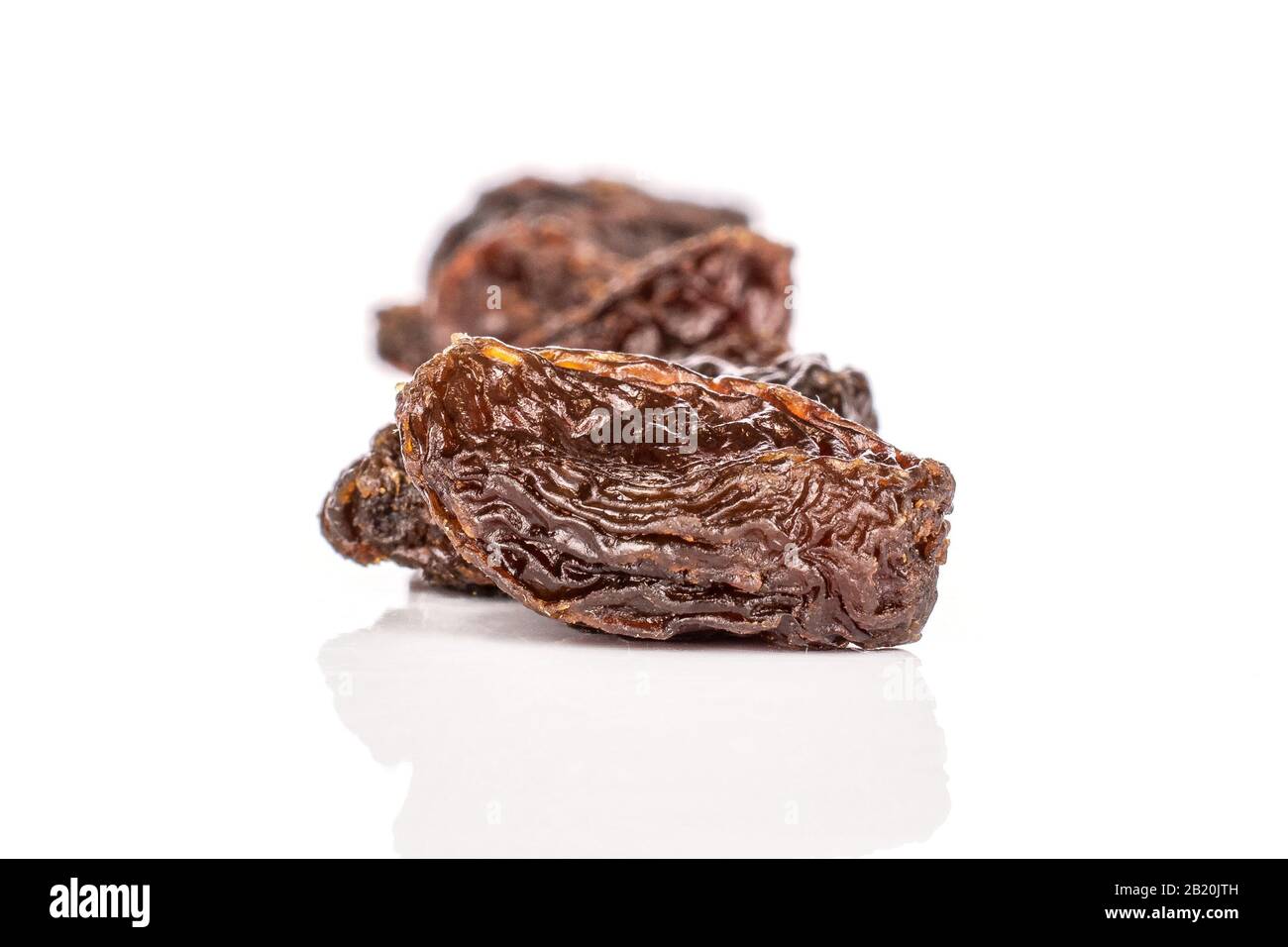 Lot of whole dried dark raisin in row isolated on white background ...