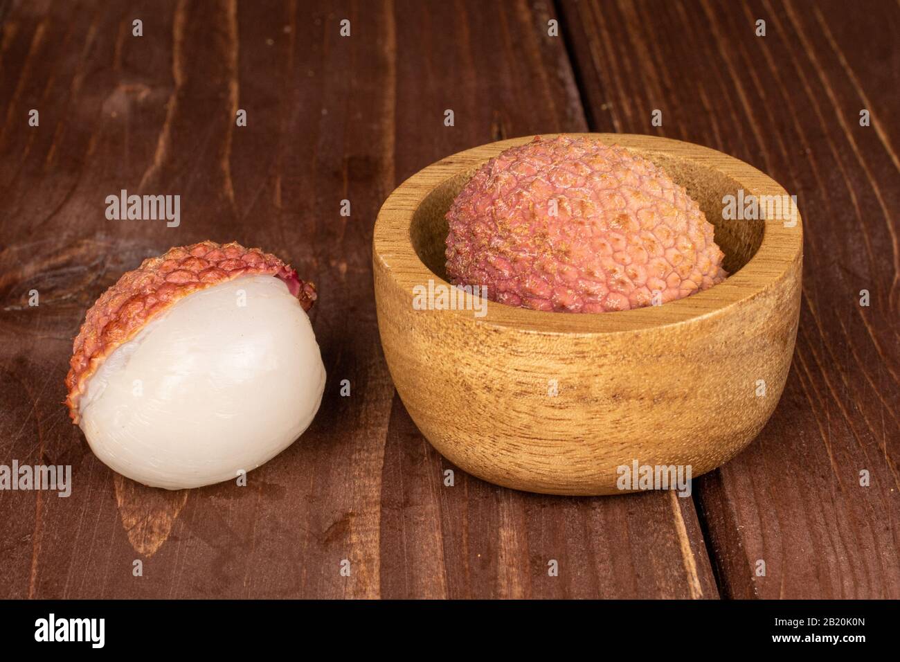 Group of two whole fresh lychee in bamboo bowl on brown wood Stock ...