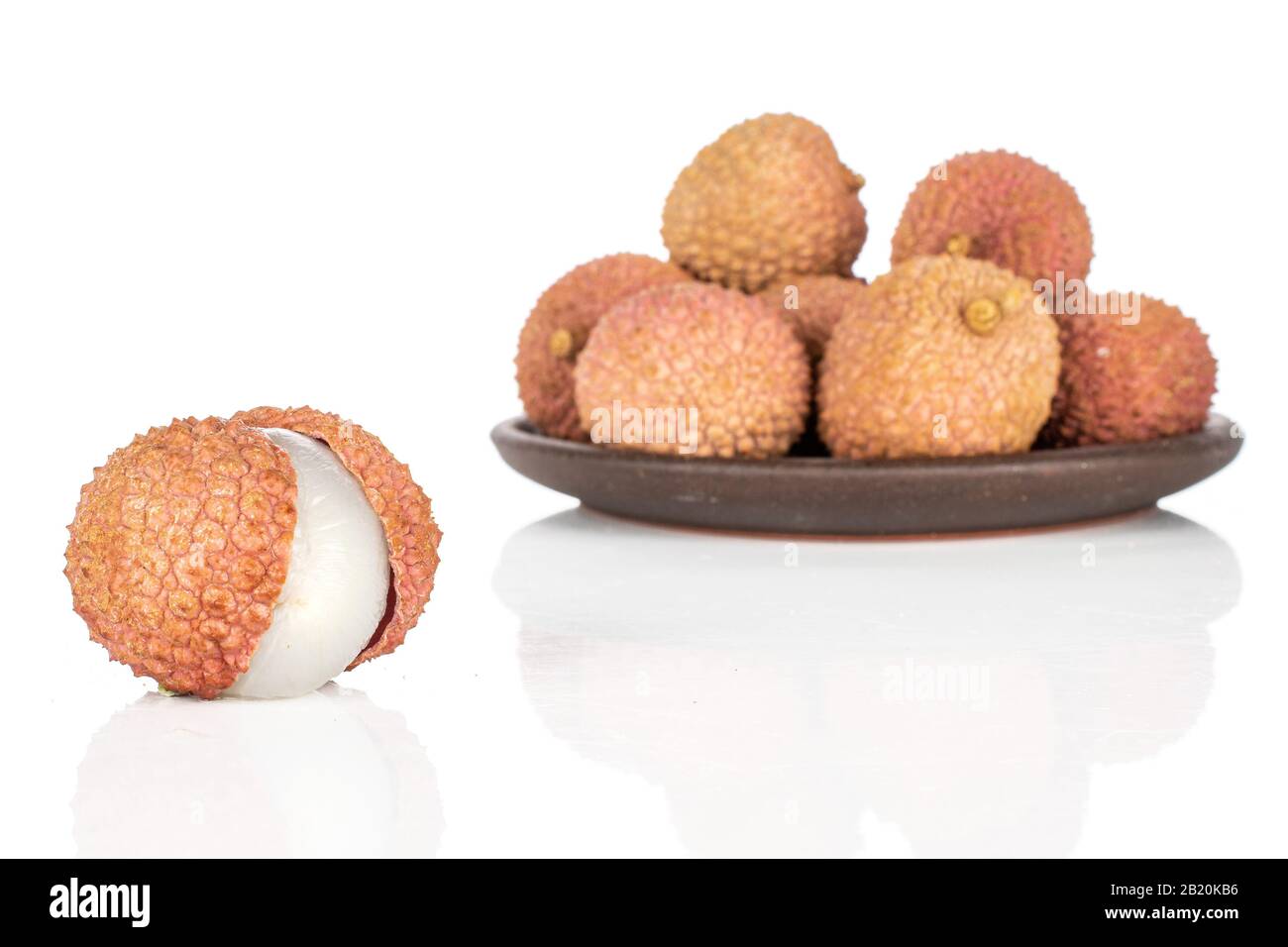 Group of eight whole fresh lychee with brown ceramic coaster isolated ...