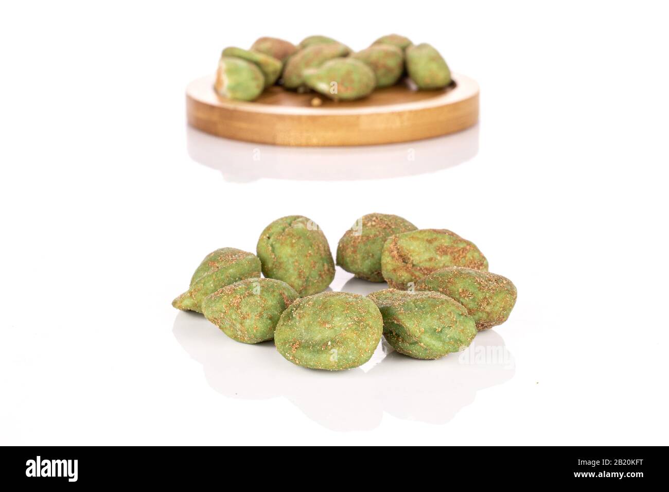Lot of whole small wasabi green peanut on round bamboo coaster isolated ...