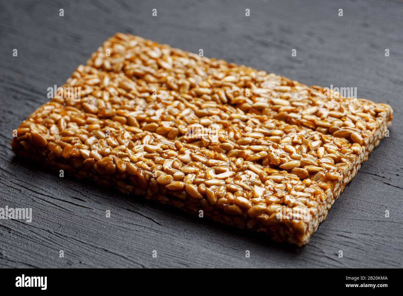 Tile kozinaki from sunflower seeds on a black textural background ...